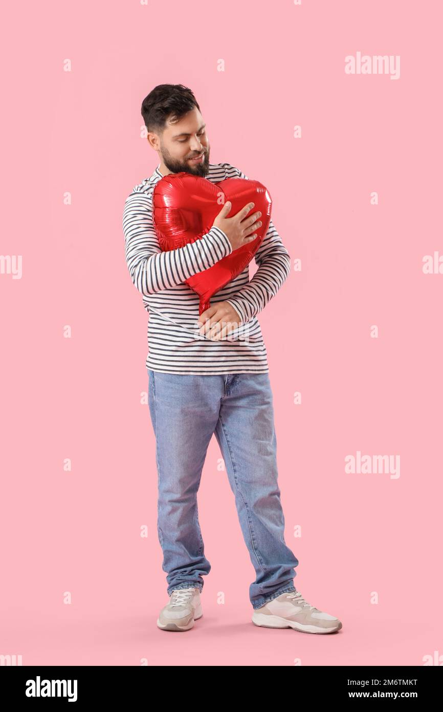 Young bearded man with balloon for Valentine's Day on pink background ...