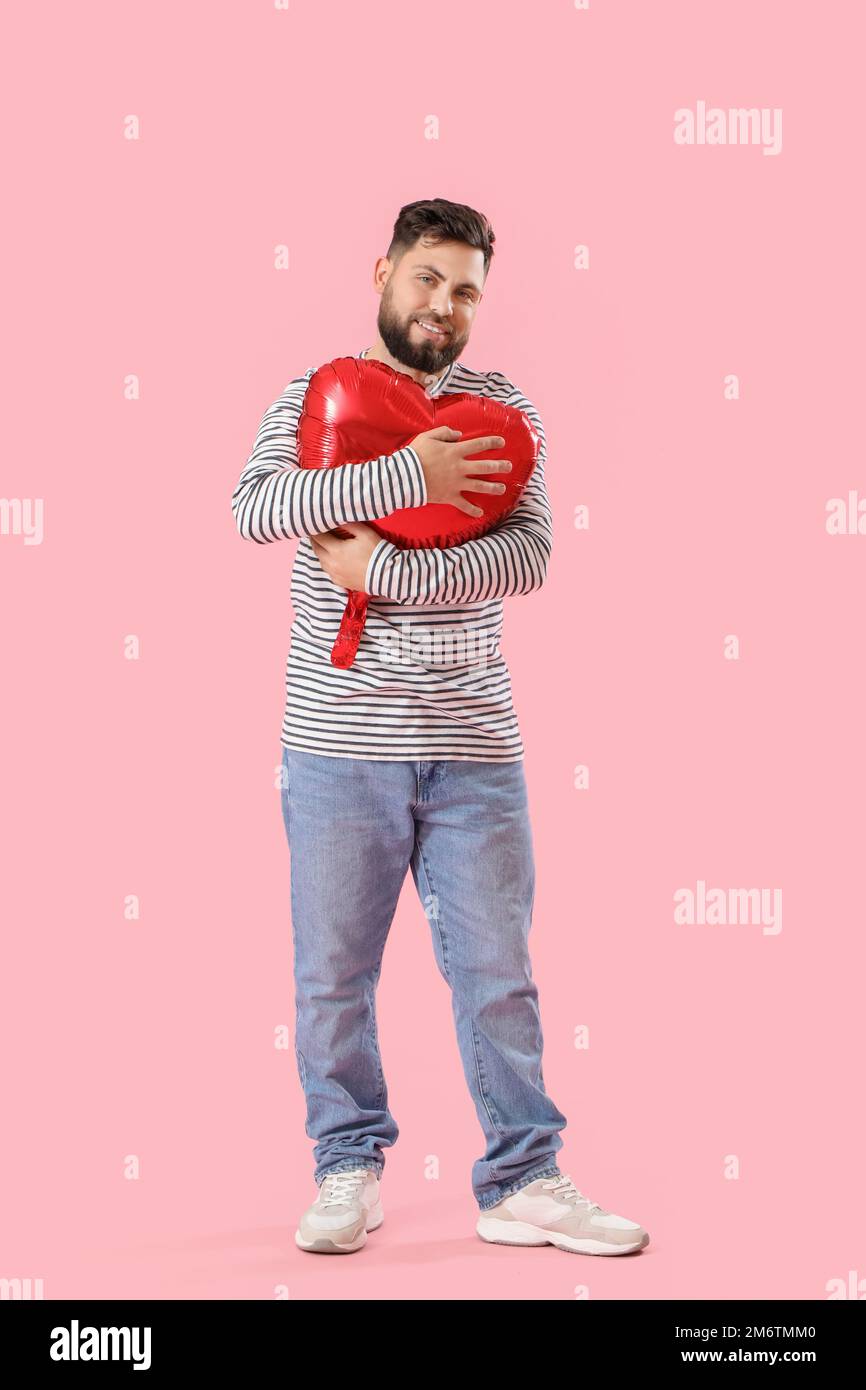 Young bearded man with balloon for Valentine's Day on pink background ...