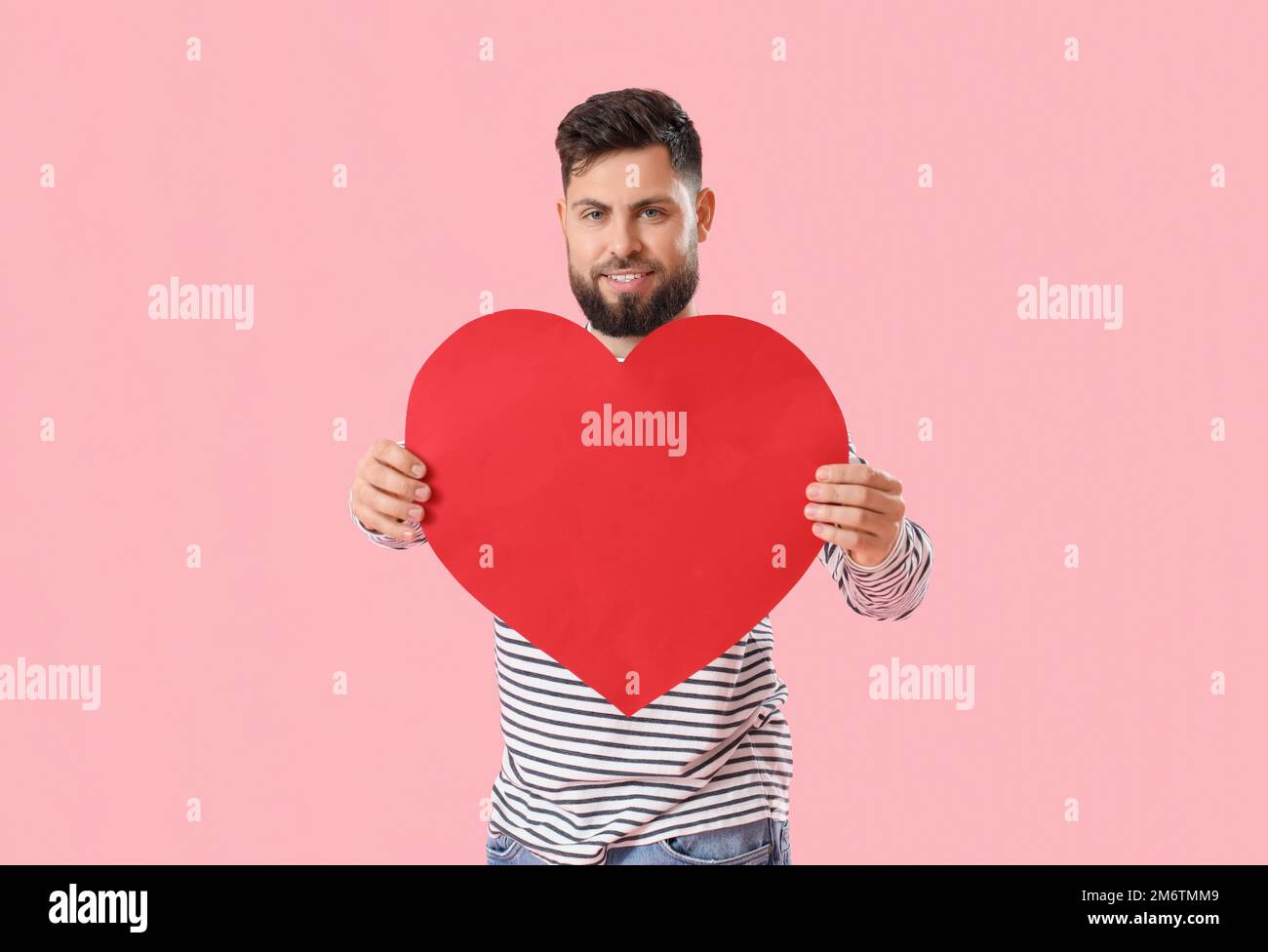Young bearded man with big paper heart for Valentine's Day on pink ...