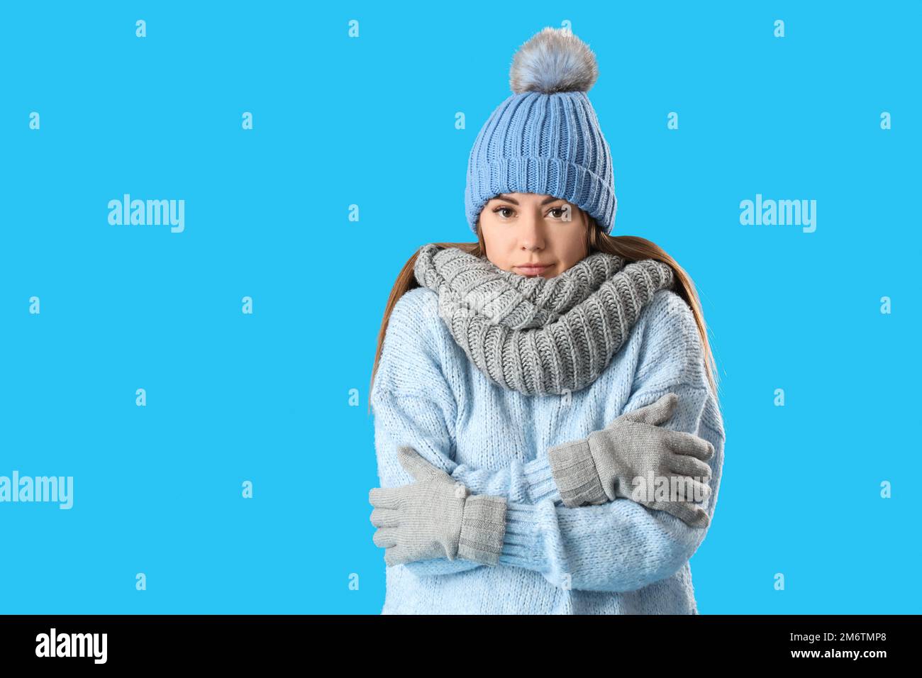 Frozen young woman in winter clothes on blue background Stock Photo - Alamy