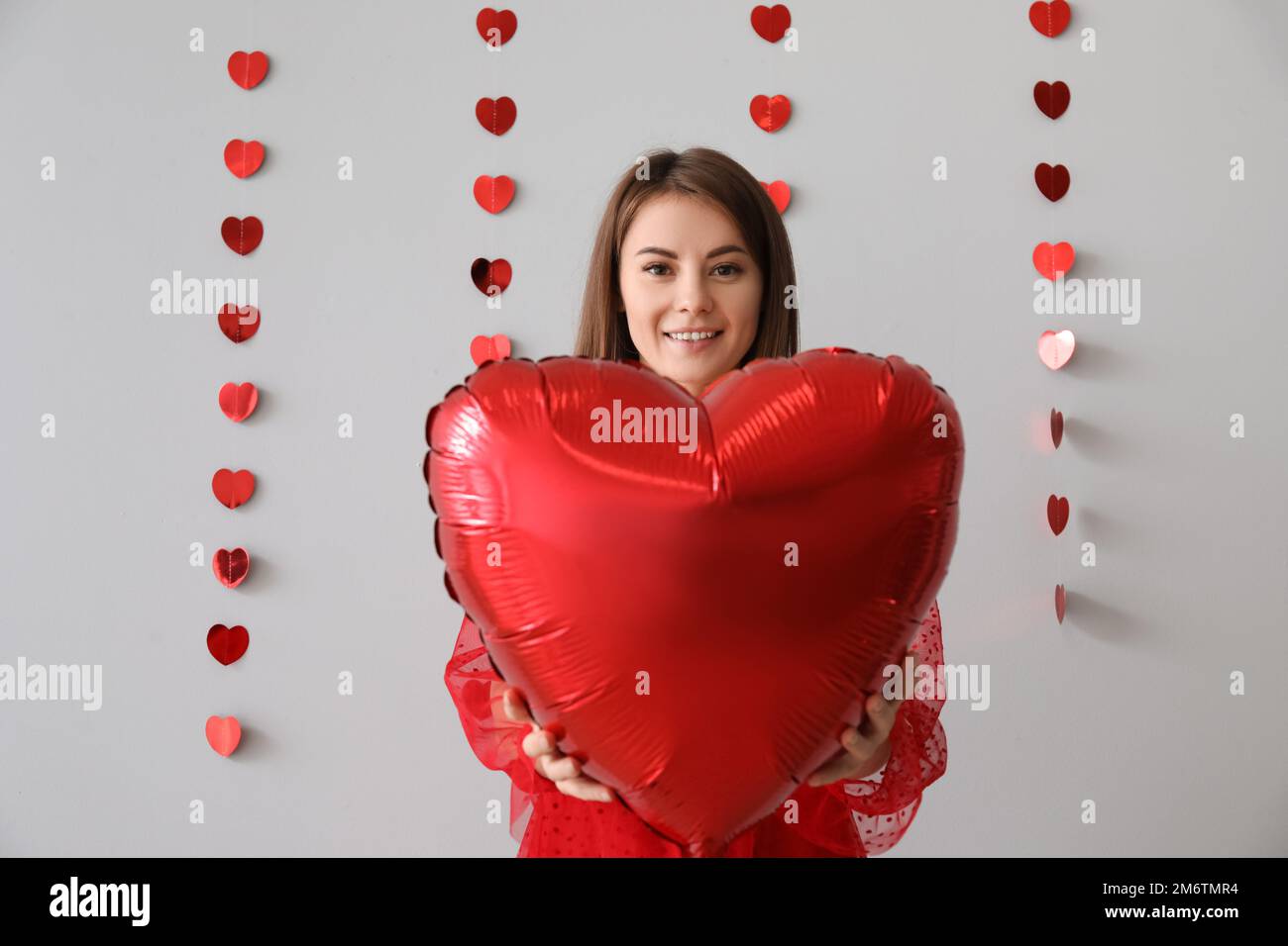 Young woman with balloon for Valentine's Day on grey background Stock ...