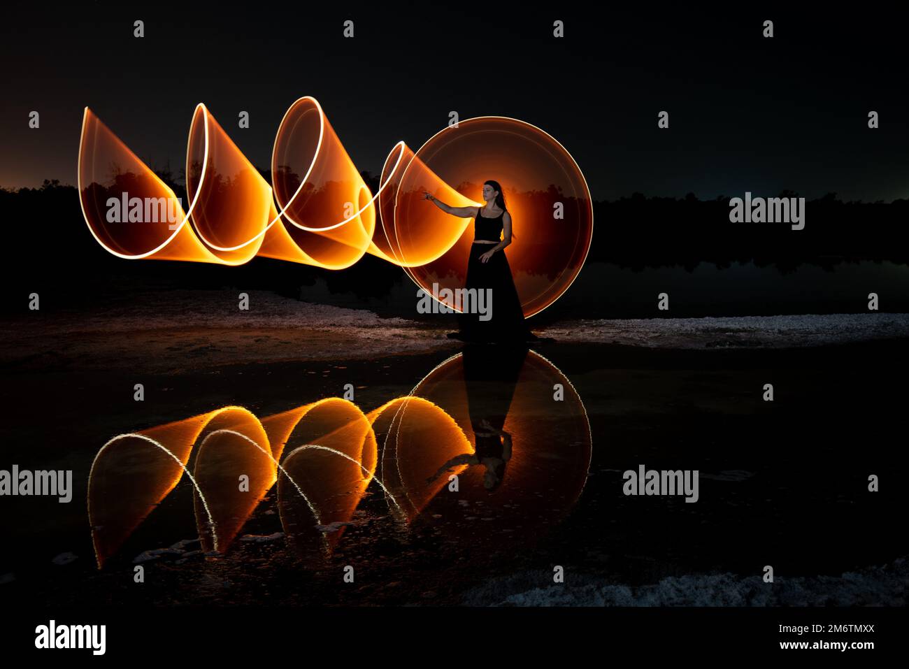 Woman posing for light painting with bright lights in the dark ...