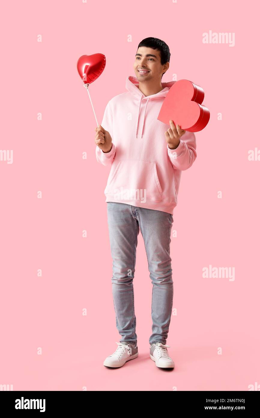Young man with balloon and gift on pink background. Valentine's Day ...