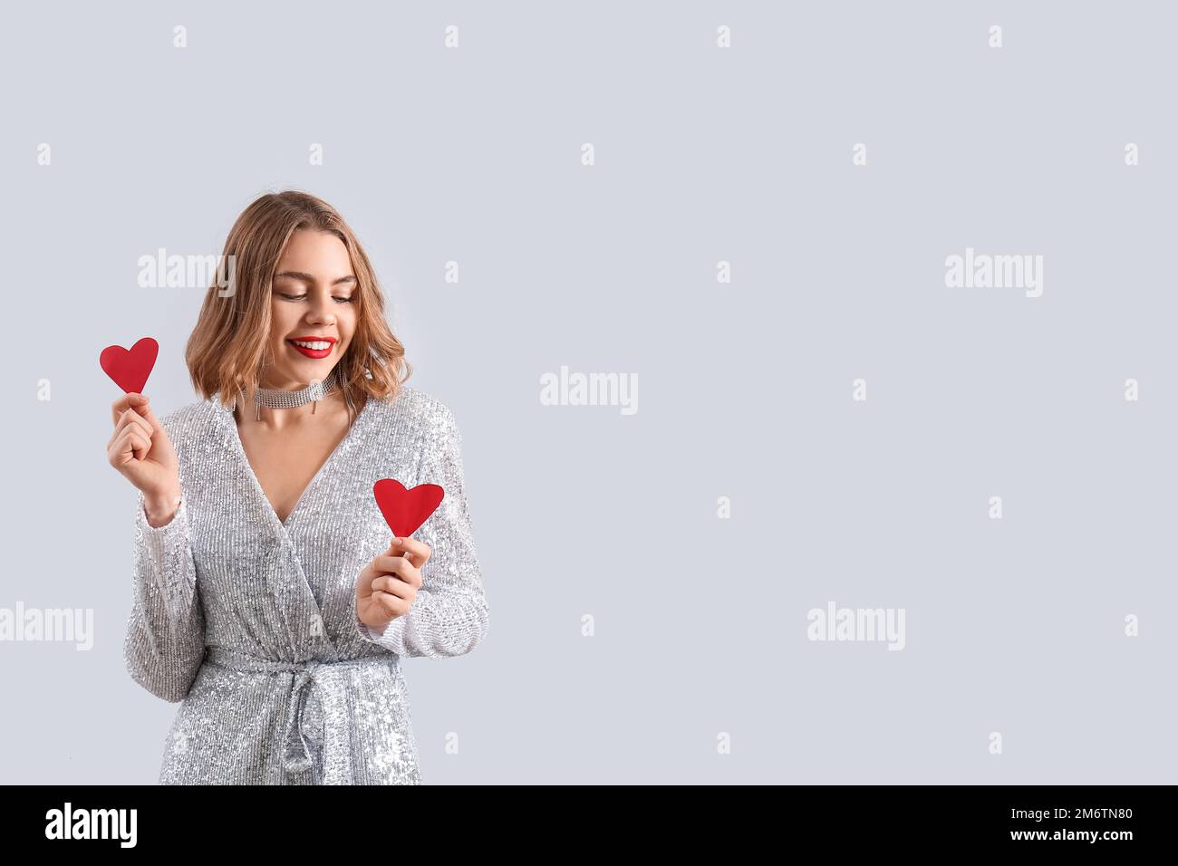 Beautiful young woman with small red hearts on light background Stock ...