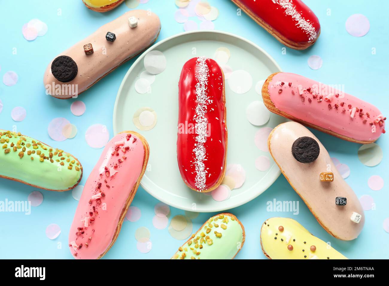 Plate and various glazed eclairs on blue background Stock Photo - Alamy