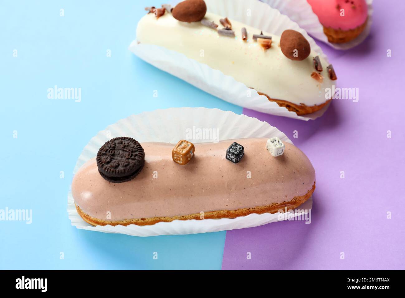 Various glazed eclairs on blue and lilac background Stock Photo - Alamy
