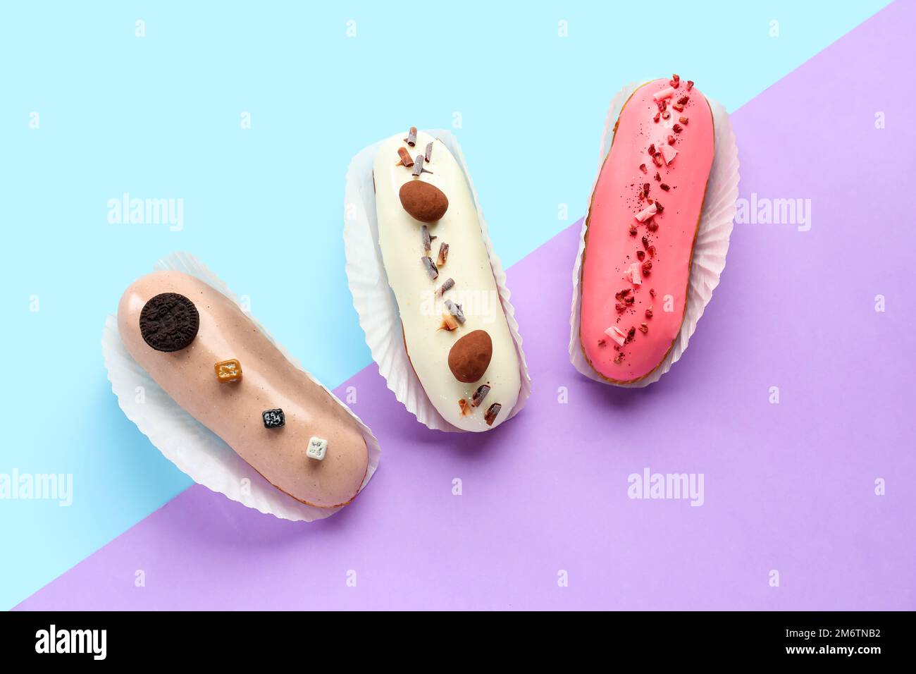 Various glazed eclairs on blue and lilac background Stock Photo - Alamy