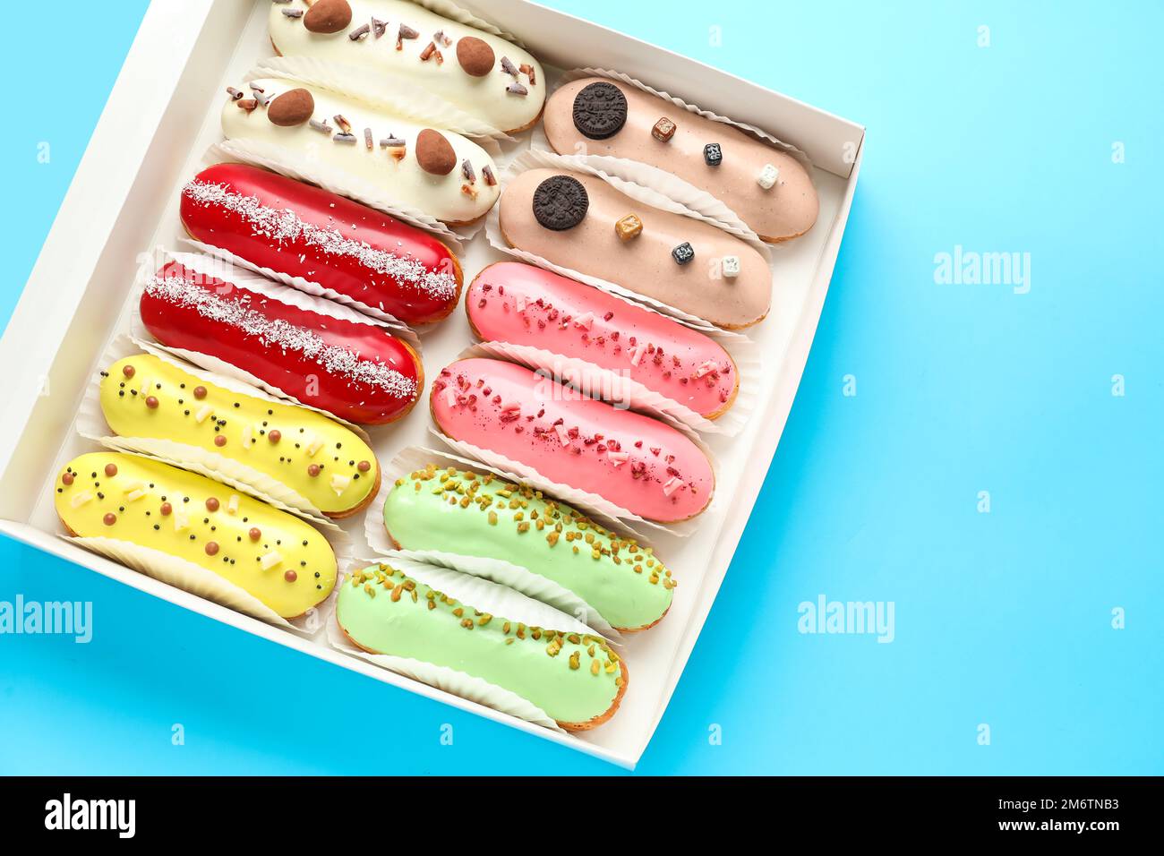 Box with various glazed eclairs on blue background Stock Photo - Alamy