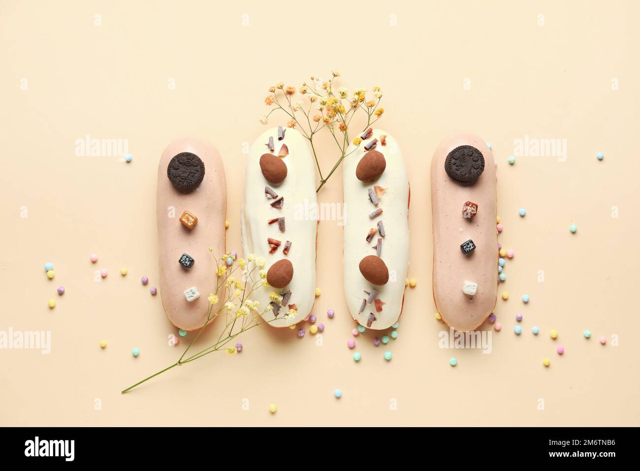 Delicious glazed eclairs and floral decor on beige background Stock ...