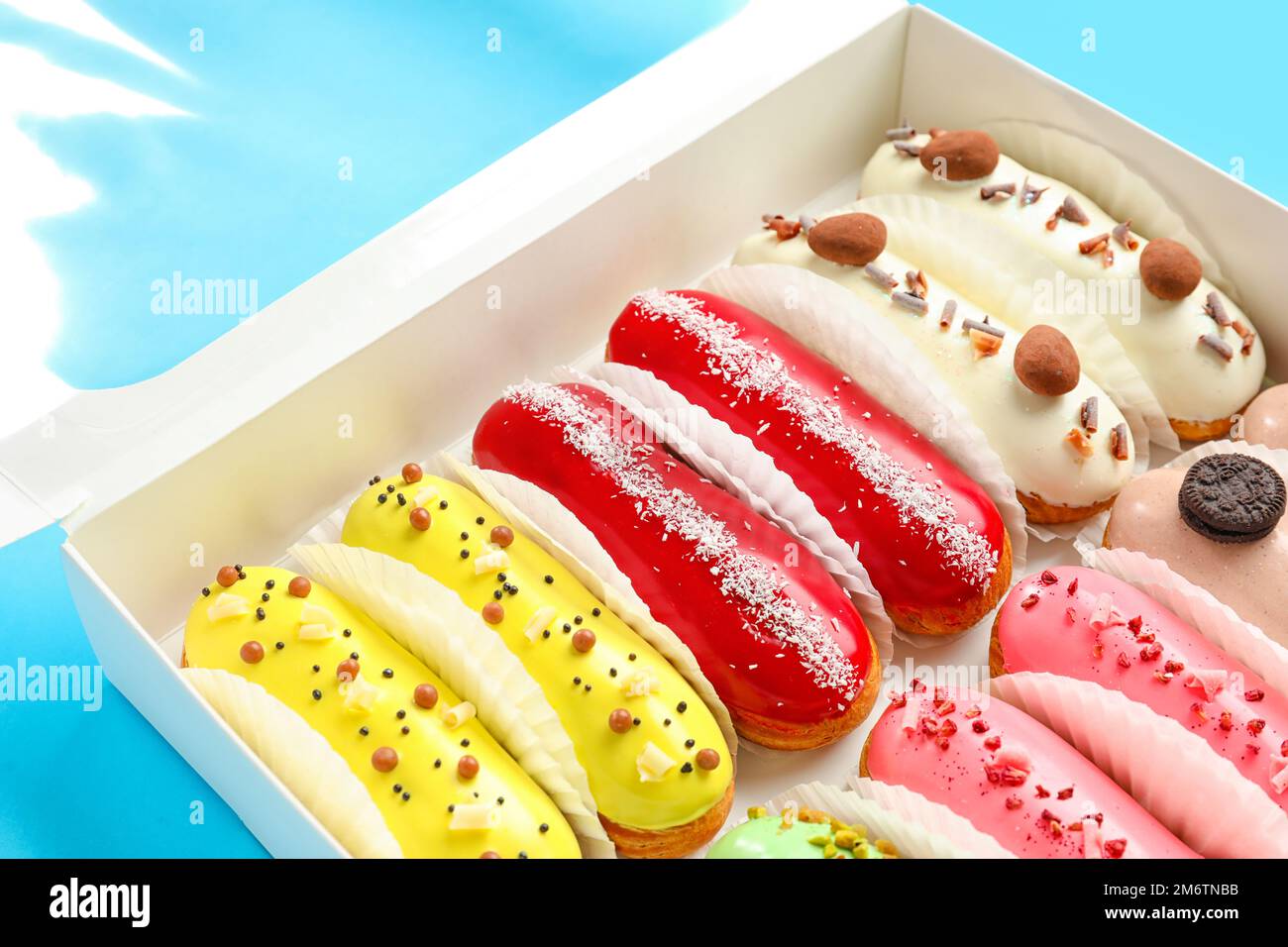Box with various glazed eclairs on blue background Stock Photo - Alamy