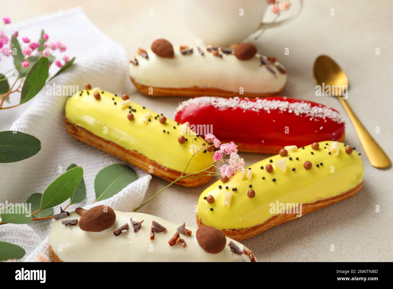 Delicious glazed eclairs and floral decor on grey background Stock ...