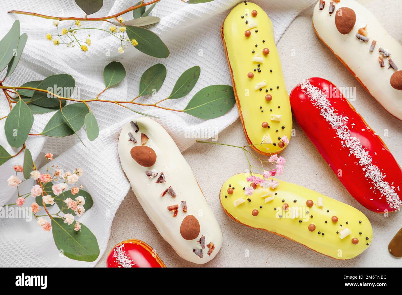 Delicious glazed eclairs and floral decor on grey background Stock ...