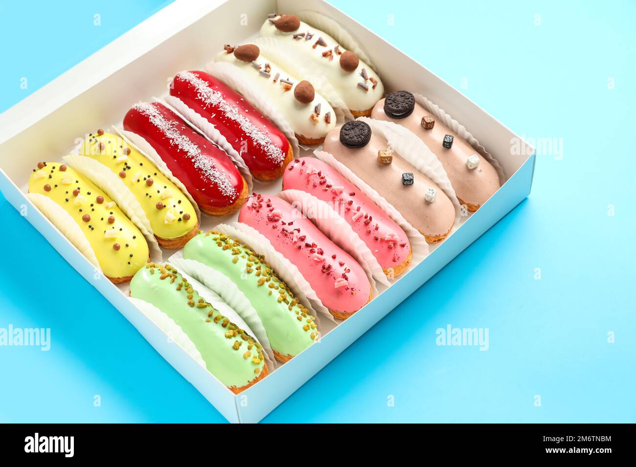 Box with various glazed eclairs on blue background Stock Photo - Alamy