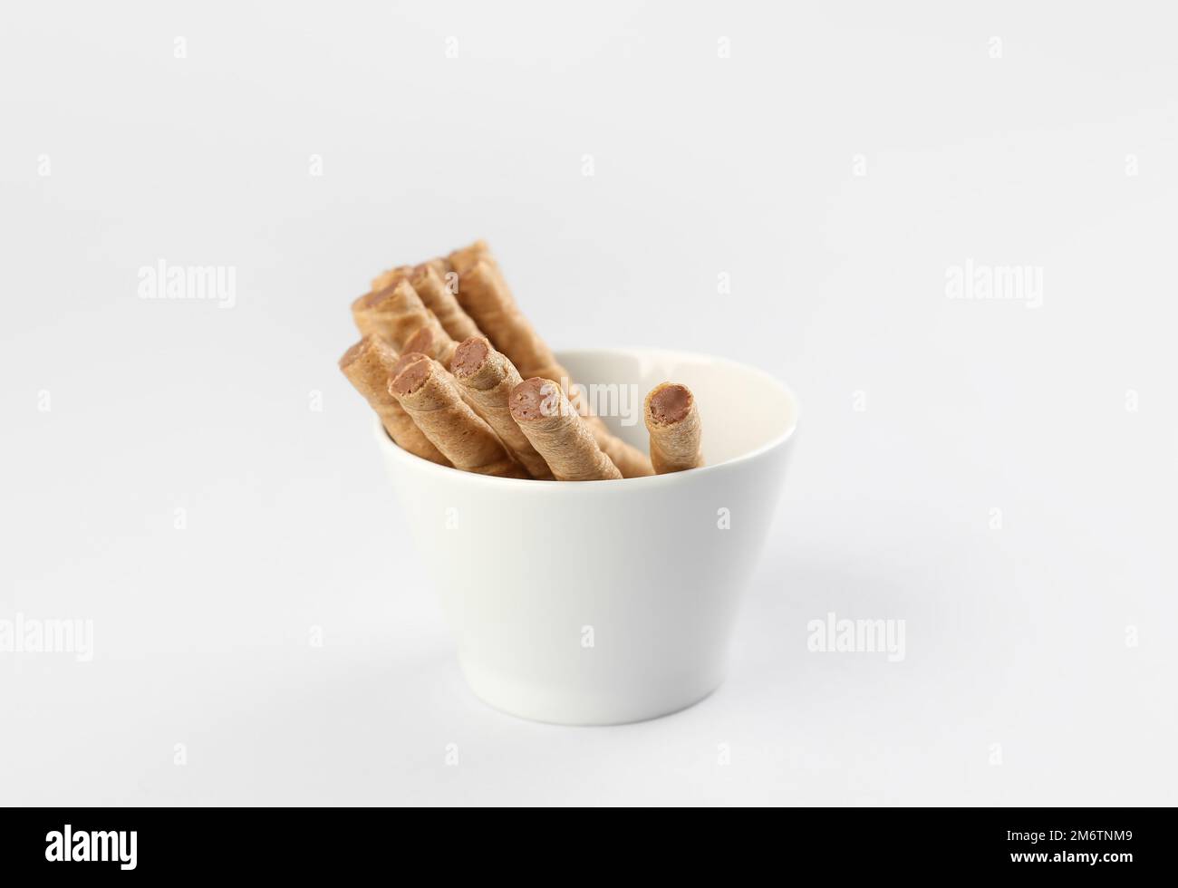 Bowl of tasty wafer rolls with condensed boiled milk on grey background ...