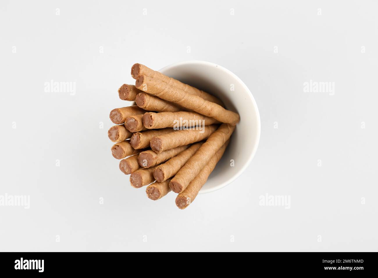 Bowl of tasty wafer rolls with condensed boiled milk on grey background ...