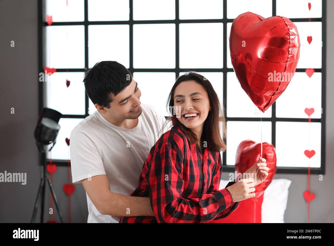 Young couple with balloon hugging in bedroom on Valentine's Day Stock ...