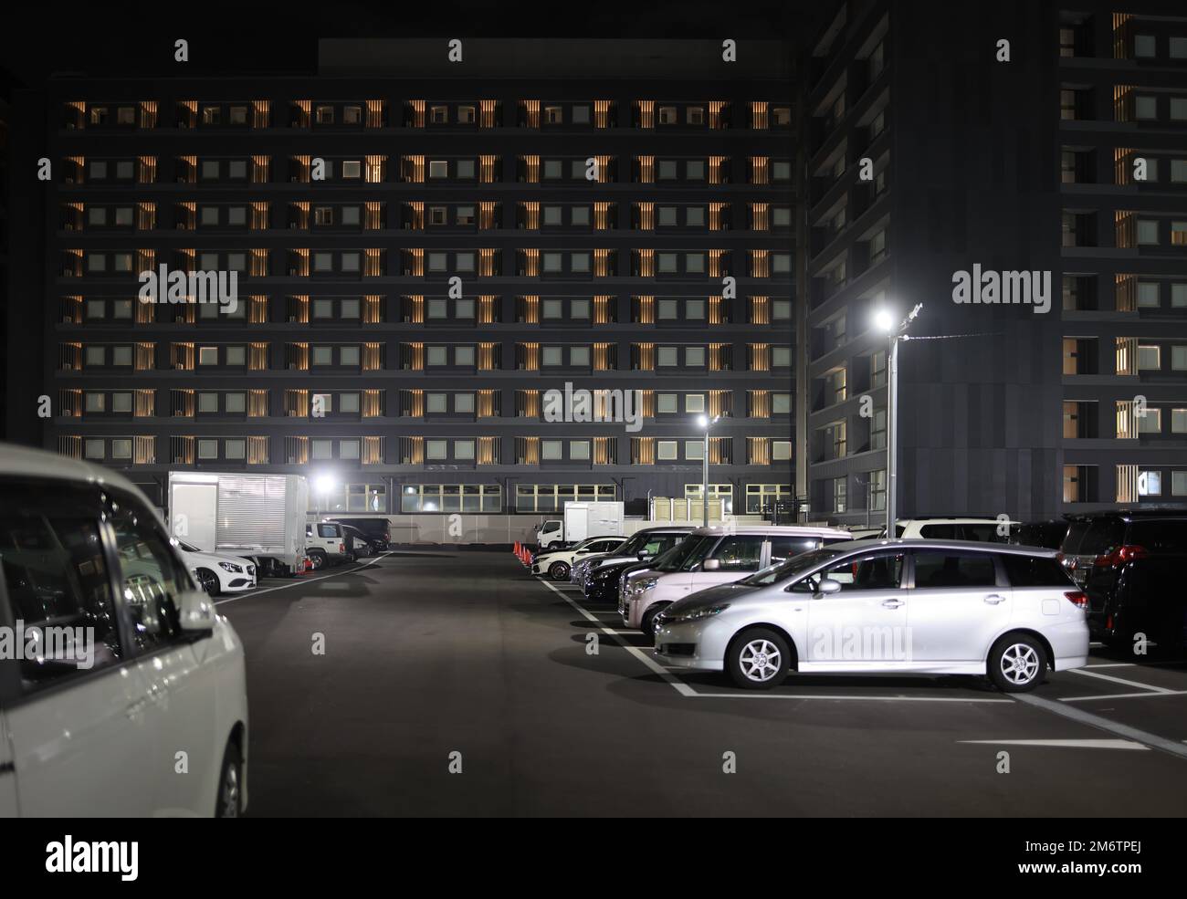 Full parking lot by multi-story hotel building at night Stock Photo - Alamy