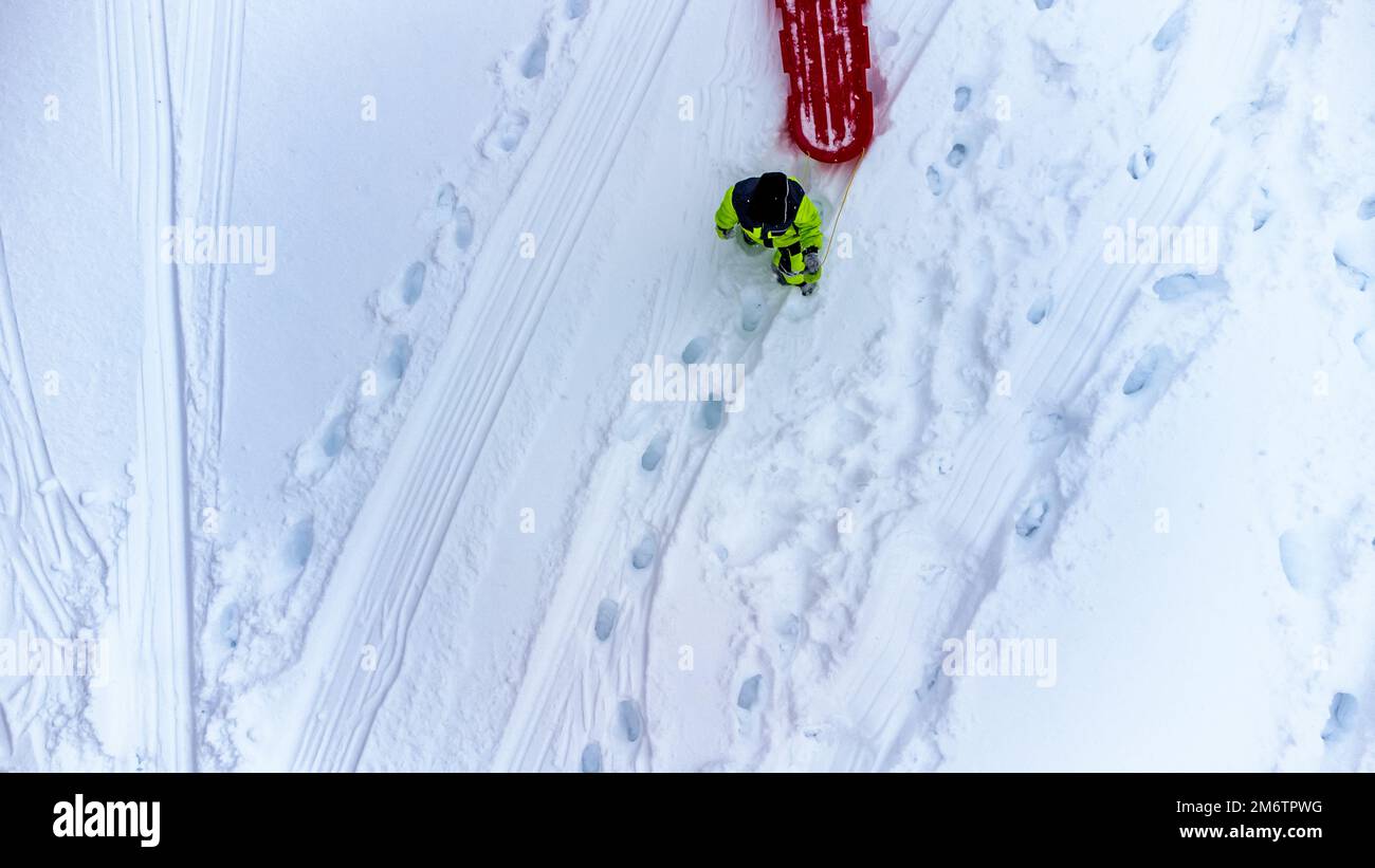 Aerial overhead drone photo of a child walking up a snow covered hill ...