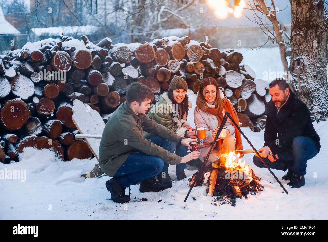 Group of friends gathering around bonfire in backyard Stock Photo - Alamy