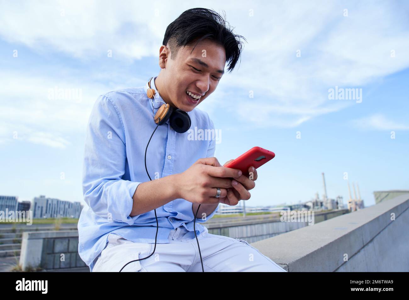 Young cheerful Asian man using smart phone cell outdoors texting and ...