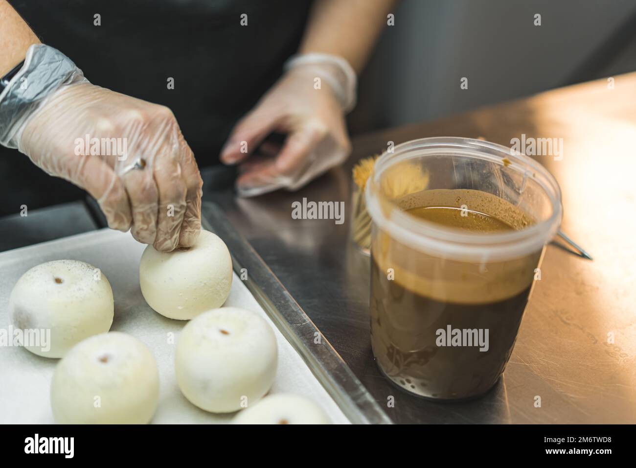 Baker is getting ready to put a round white cake into caramel icing ...