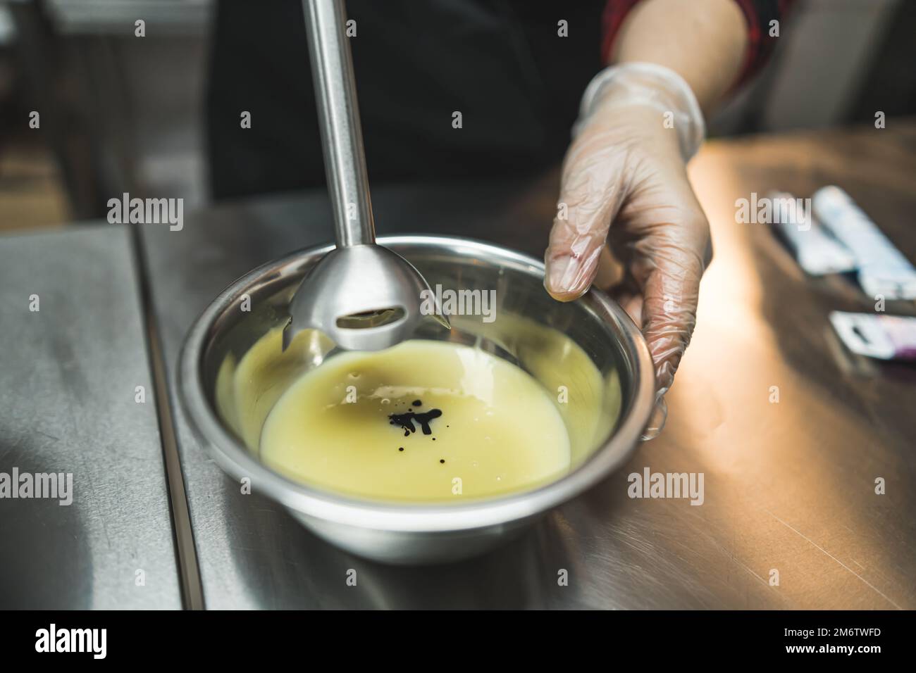 A baker wearing transparent glove about to blend white glaze with food ...