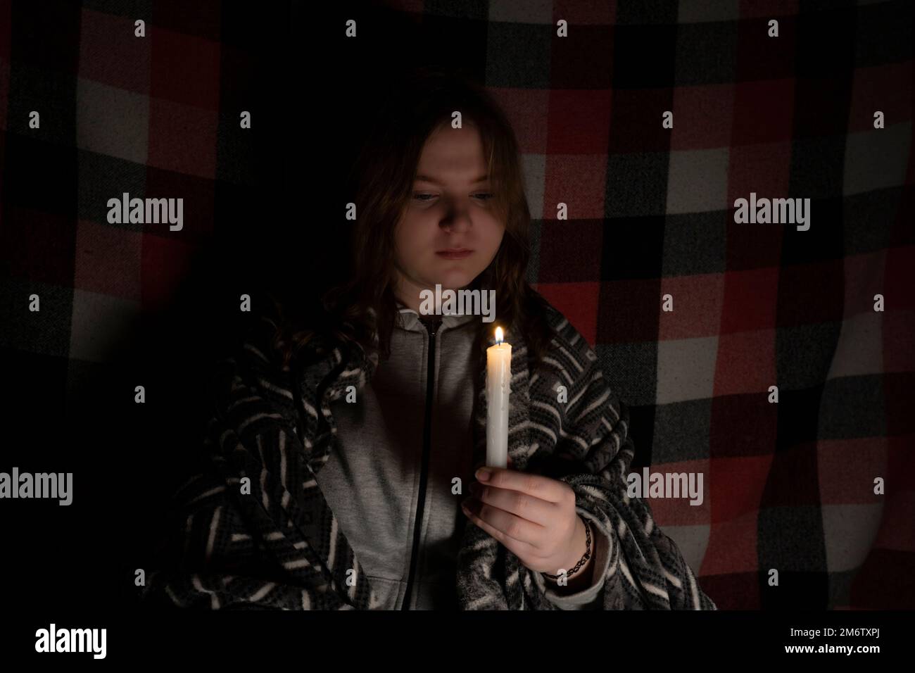 Girl with a burning candle in a dark room. Blackout. Energy crisis ...
