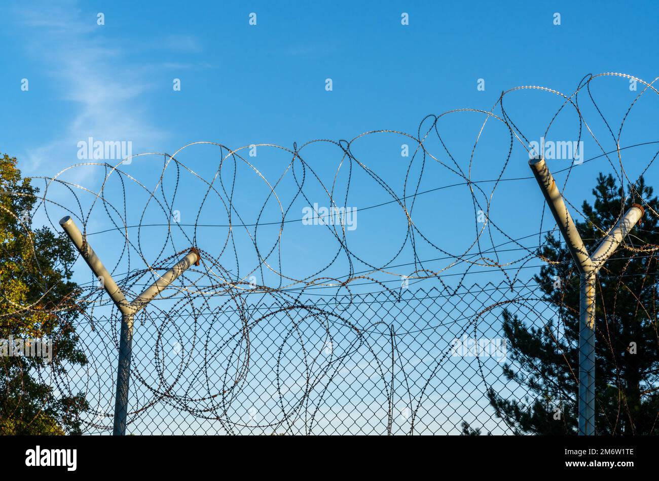 A close-up view of a tall barbed wire fence on the border between ...