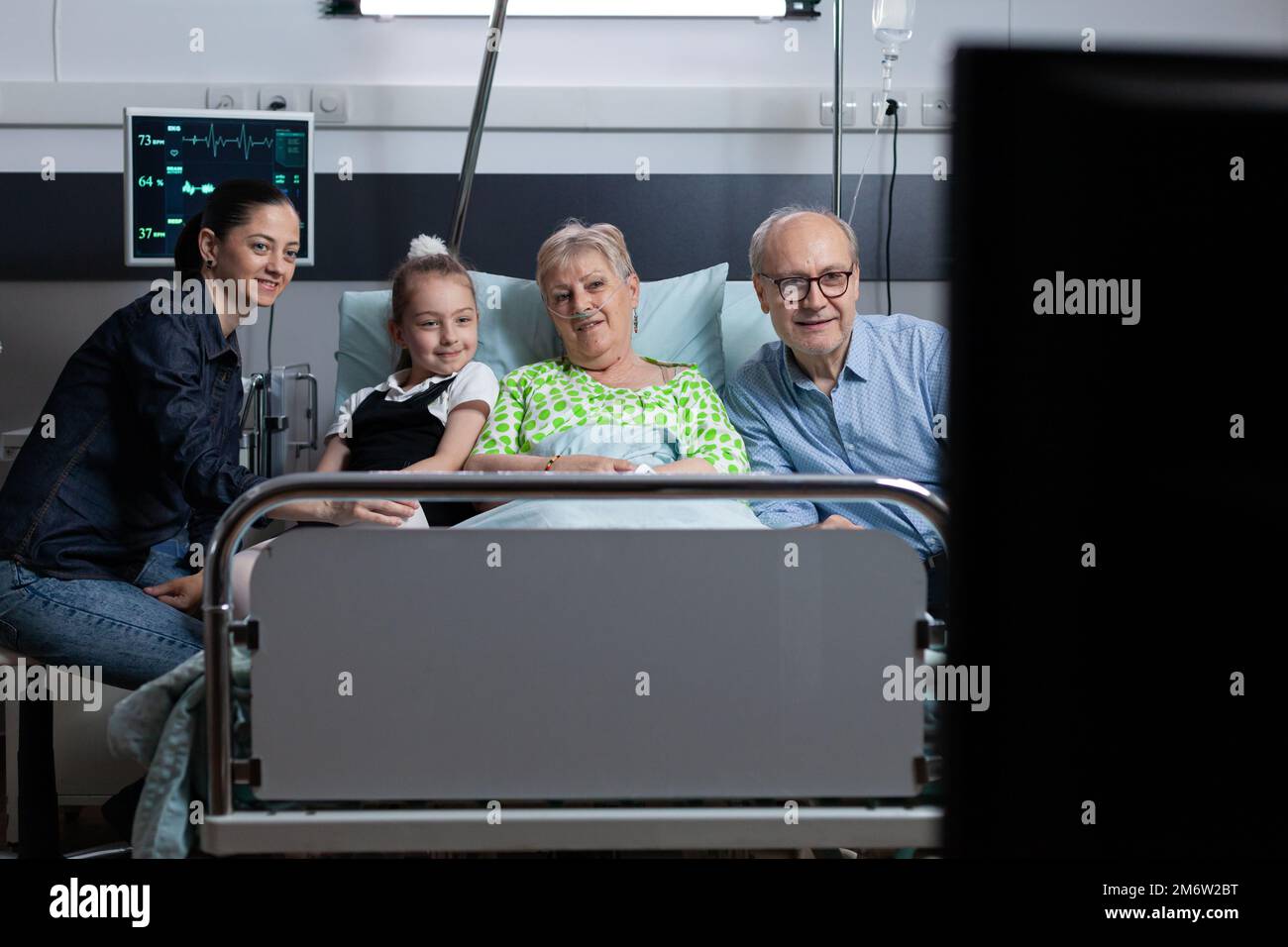 Sick elderly woman lying in hospital room bed with medical monitoring ...