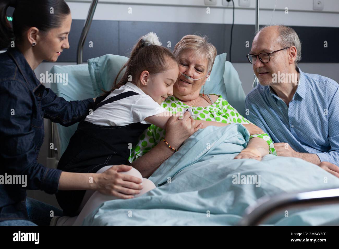 Happy little girl greeting sick grandmother with hug on hospital room ...