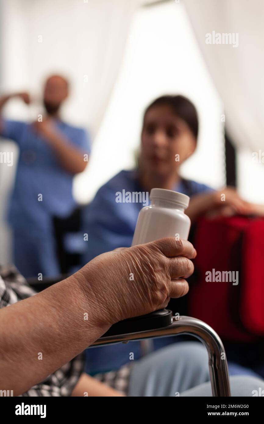 Close-up view of elderly woman in wheelchair holding bottle of pills ...