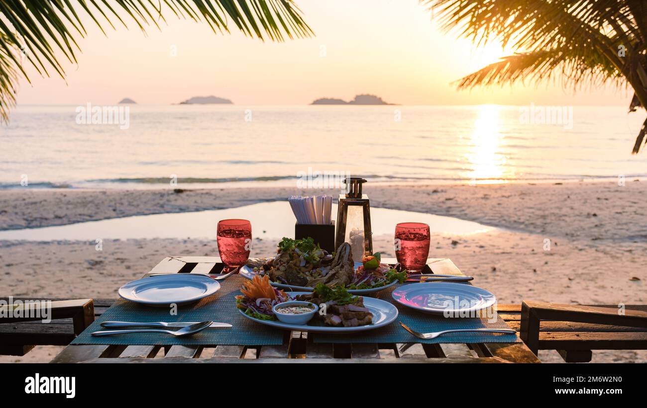 Dinner table during sunset on a beach with fish and Thai food Stock ...