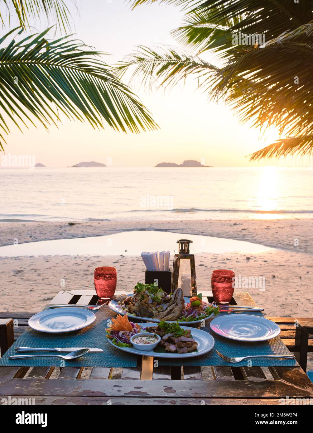 Dinner table during sunset on a beach with fish and Thai food Stock ...