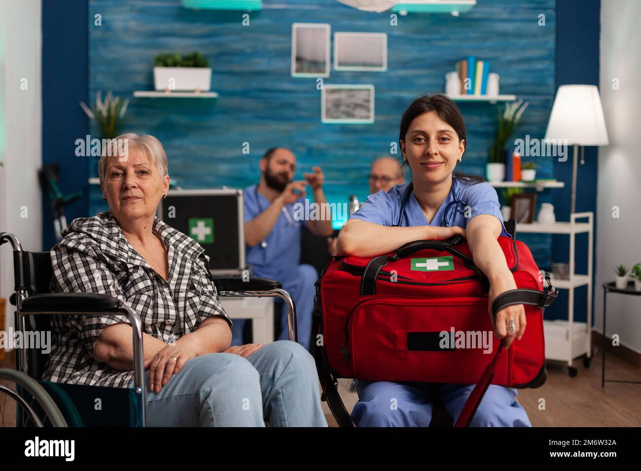 Female healthcare assistant sitting in living room of nursing home next ...