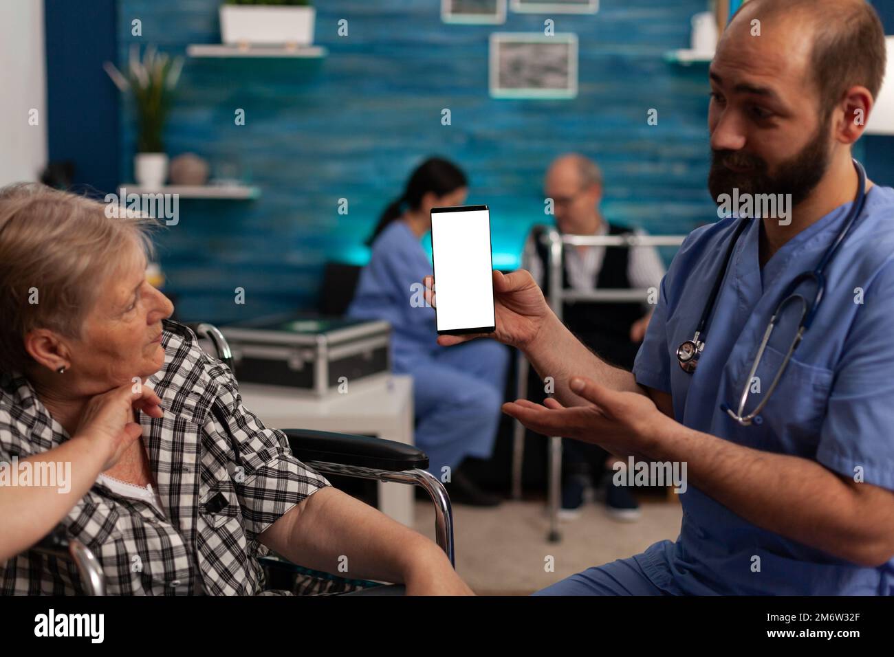 Male nurse showing white cellular screen while assisting elderly woman ...