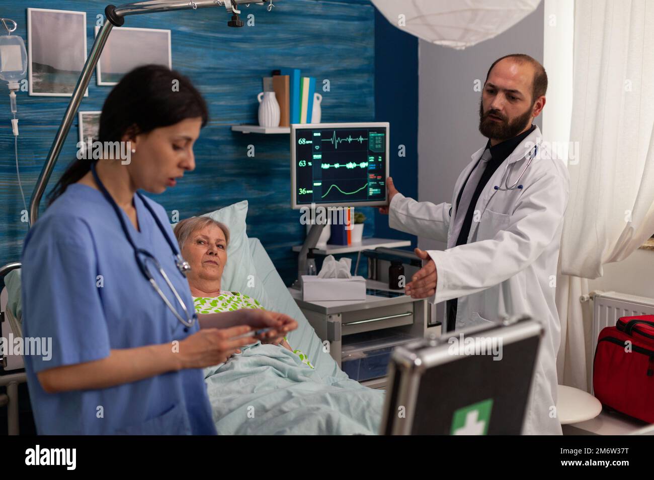 Male doctor instructing nurse on medicine to administer to elderly ...