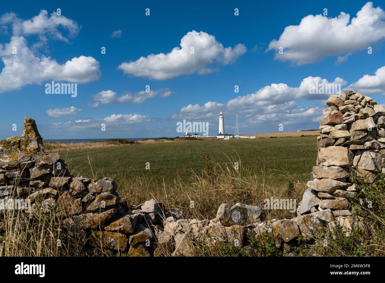 View of the Nash Point Lighthouse framed by an old stoen wall and farm ...