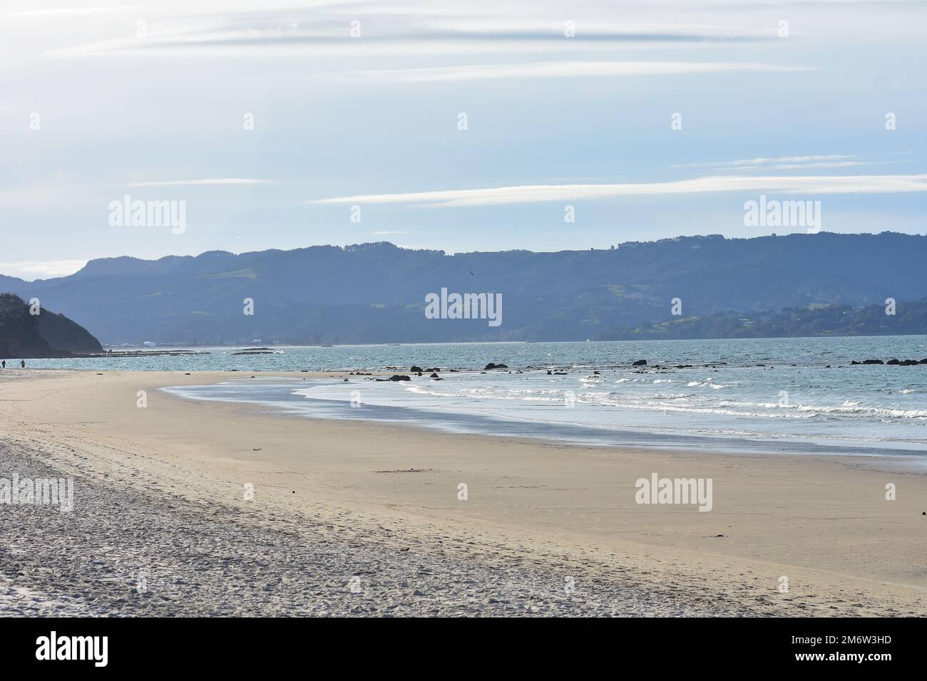 Flat sandy beach at low tide with protruding shallow water rocky reefs ...