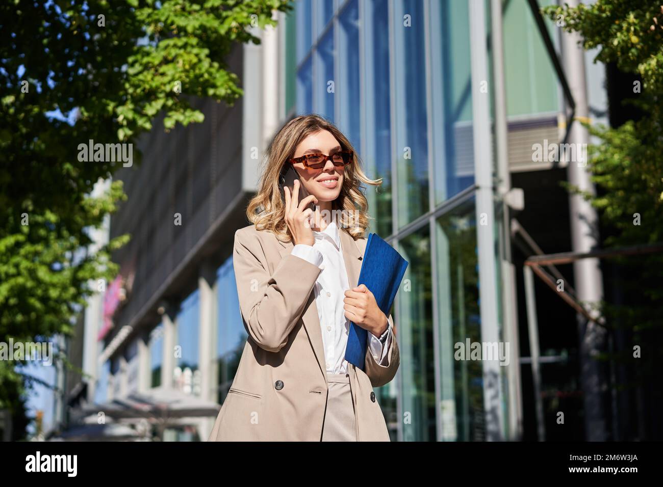 Young successful businesswoman talking on mobile phone, holding ...