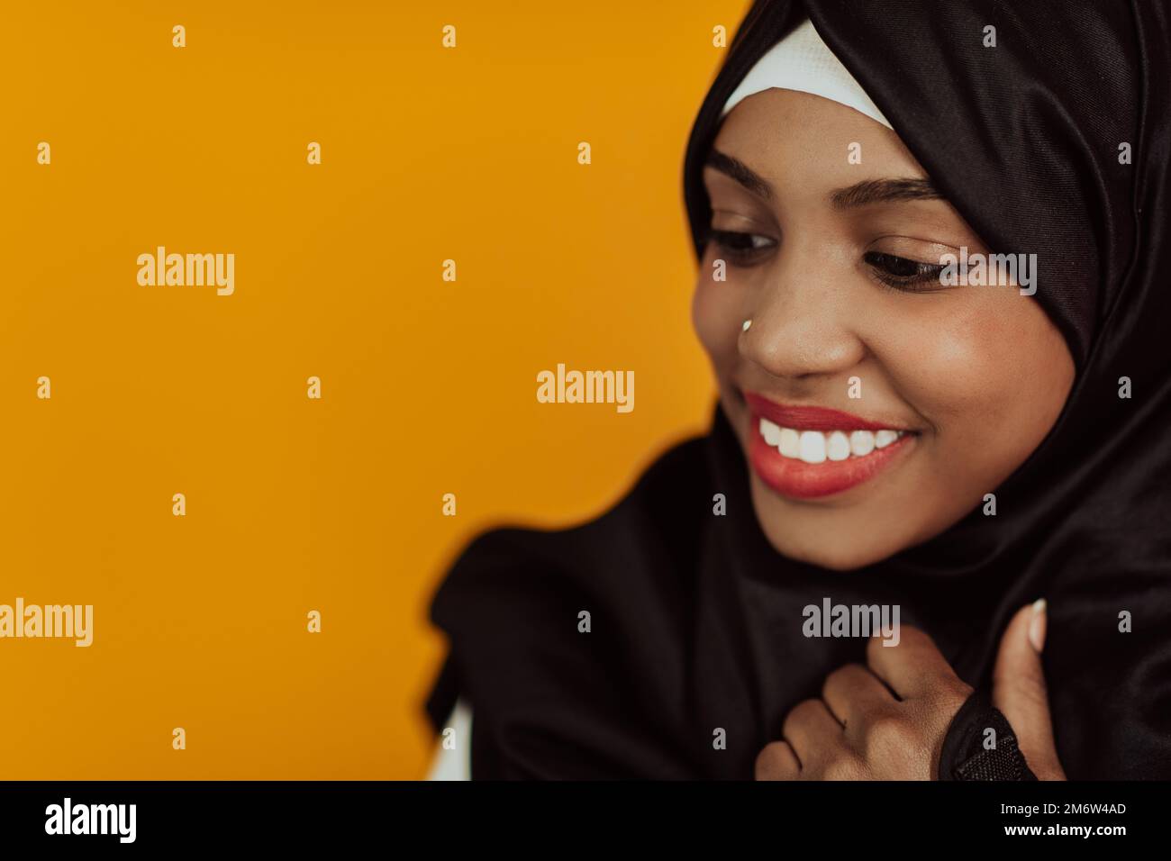 Muslim woman with a beautiful smile wearing a hijab poses in the studio ...