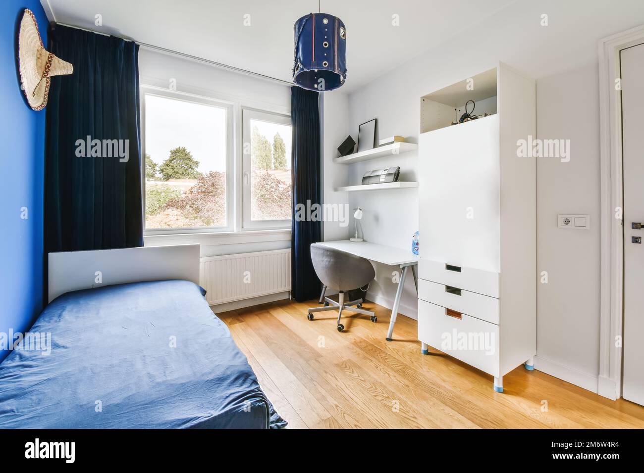 a bedroom with a bed, desk and window in the corner to the right is a ...