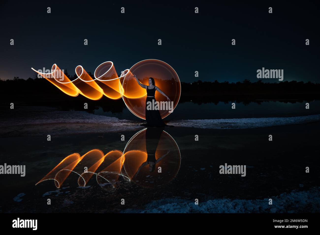 Woman posing for light painting with bright lights in the dark ...
