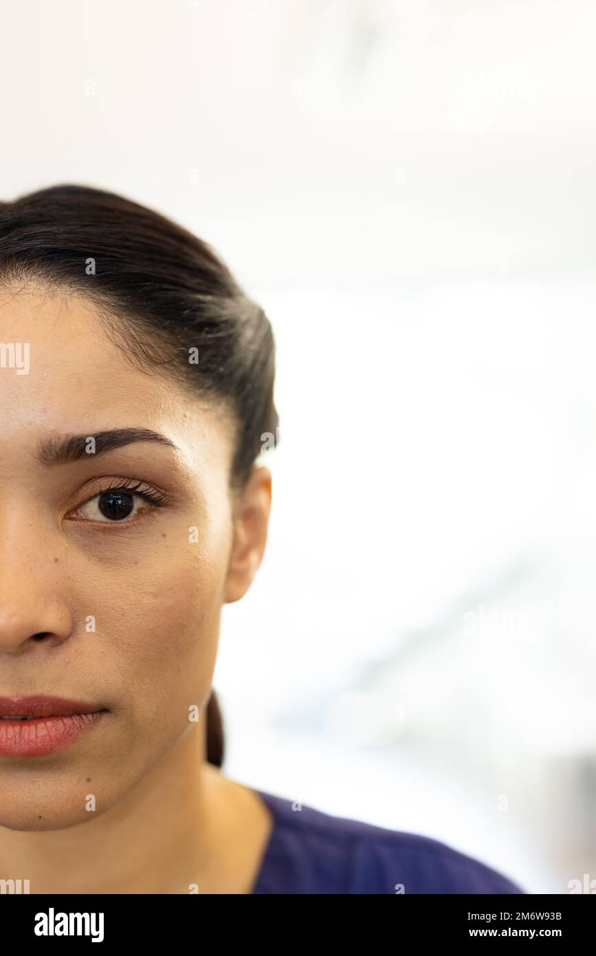 Vertical half face portrait of biracial female healthcare worker in ...