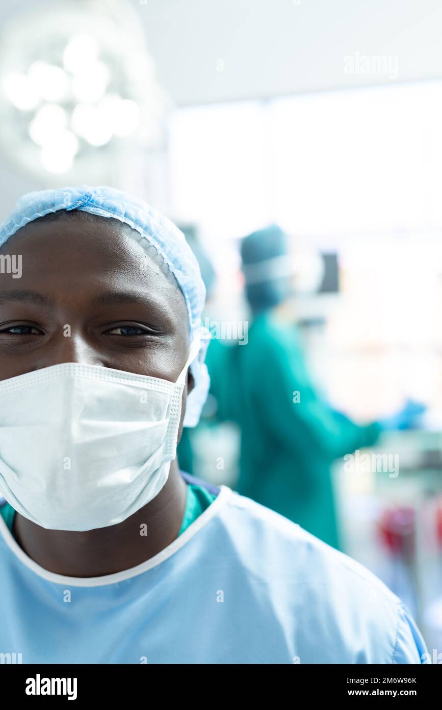 Vertical portrait of smiling african american male surgeon in mask in ...