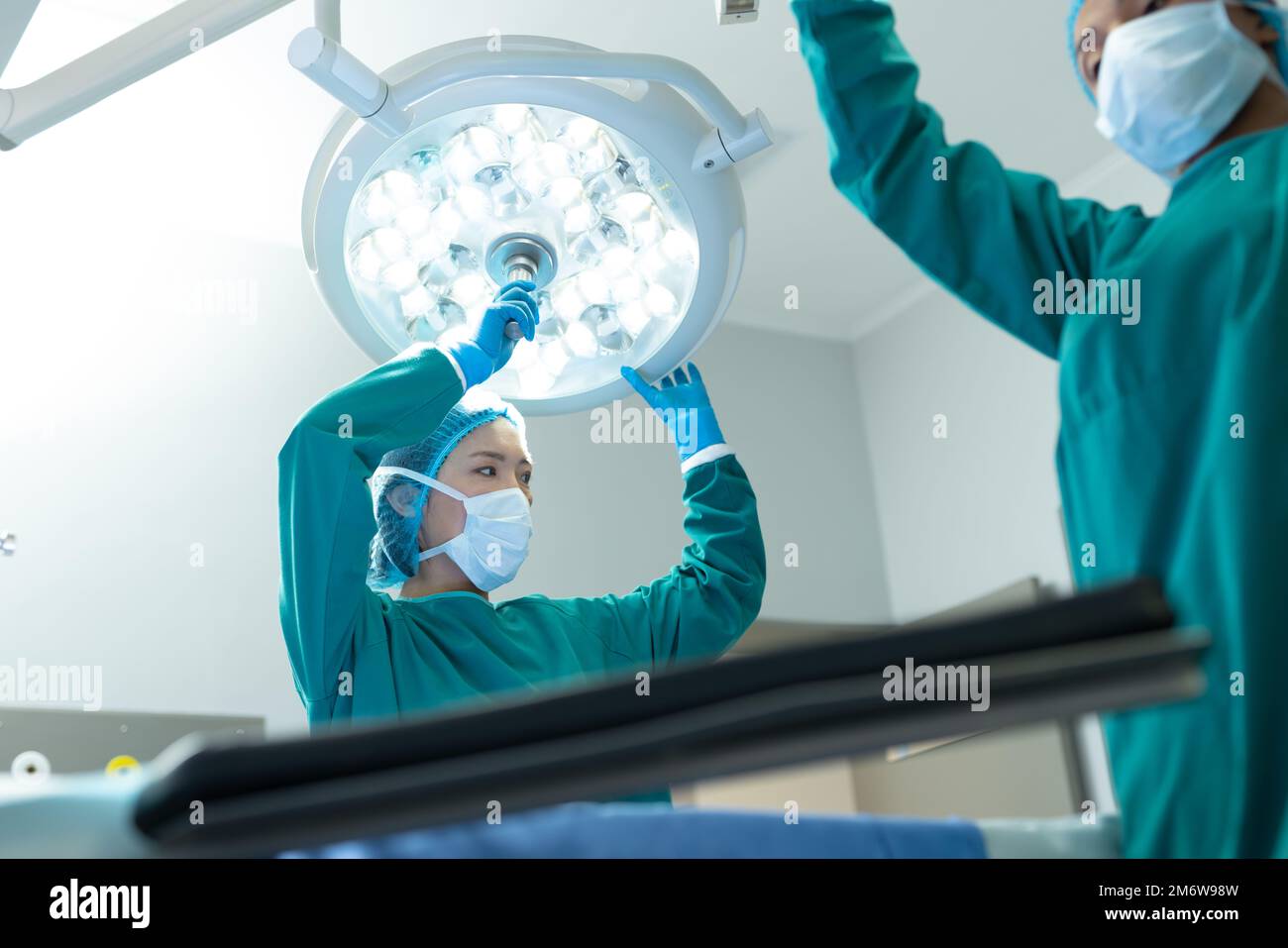Asian female surgeon and colleague adjusting lights in operating ...