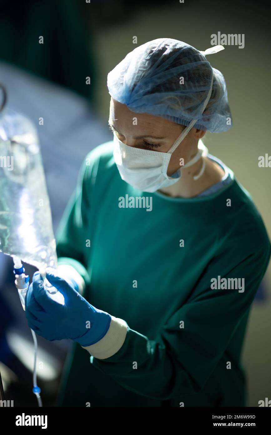 Vertical of caucasian female surgical tech preparing iv bag in ...