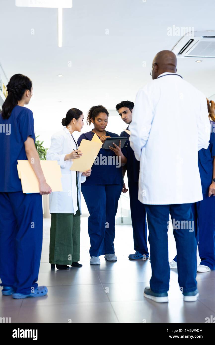 Vertical of diverse healthcare colleagues with tablet and files ...