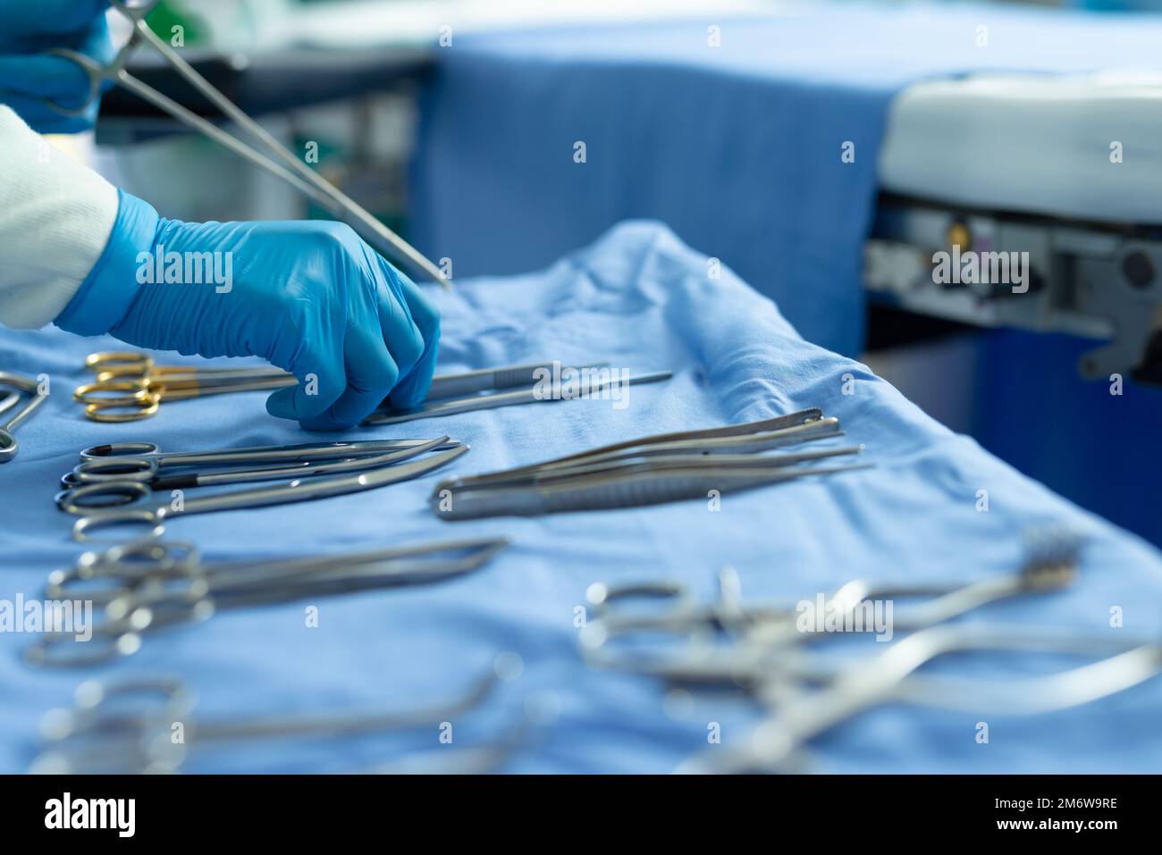 Gloved hand of surgical tech placing tools on table in operating ...
