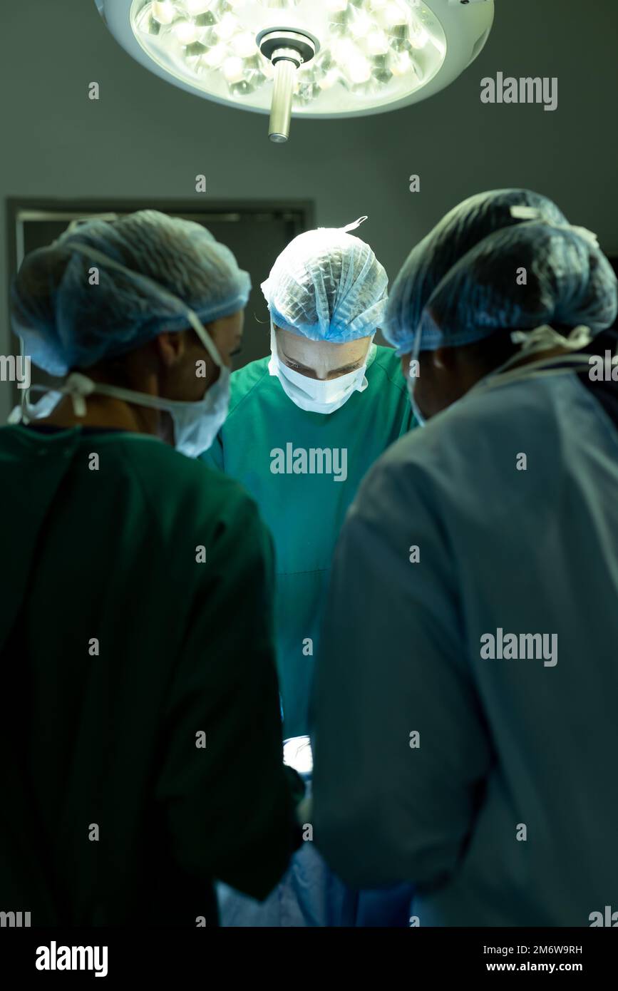 Vertical of diverse group of surgeons operating on patient in operating ...