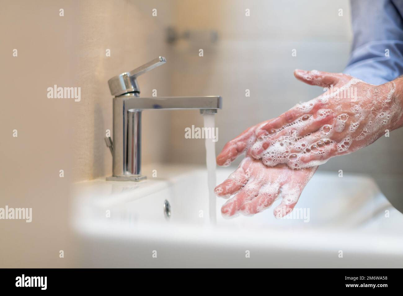 Man using soap and washing hands under the water tap. Hygiene concept ...